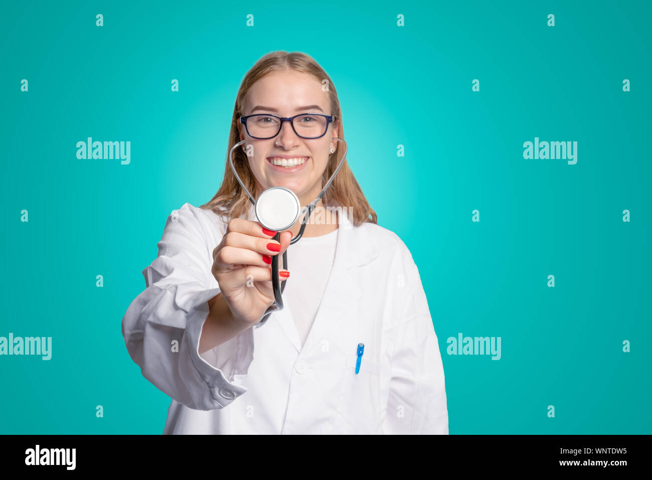 smiling female doctor is holding her stethoscope in the camera Stock ...