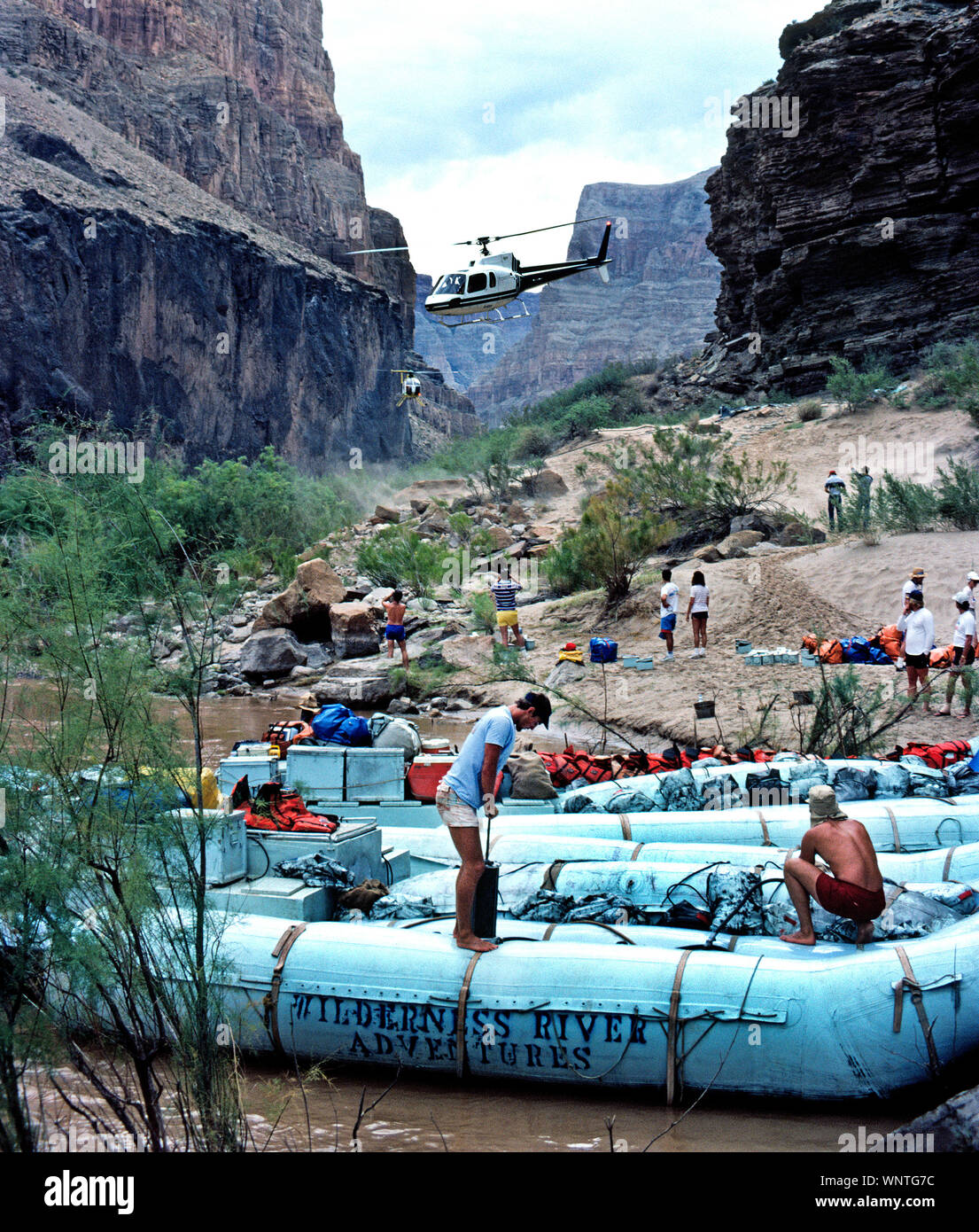 Helicopters descend between canyon walls with adventure travelers who ...