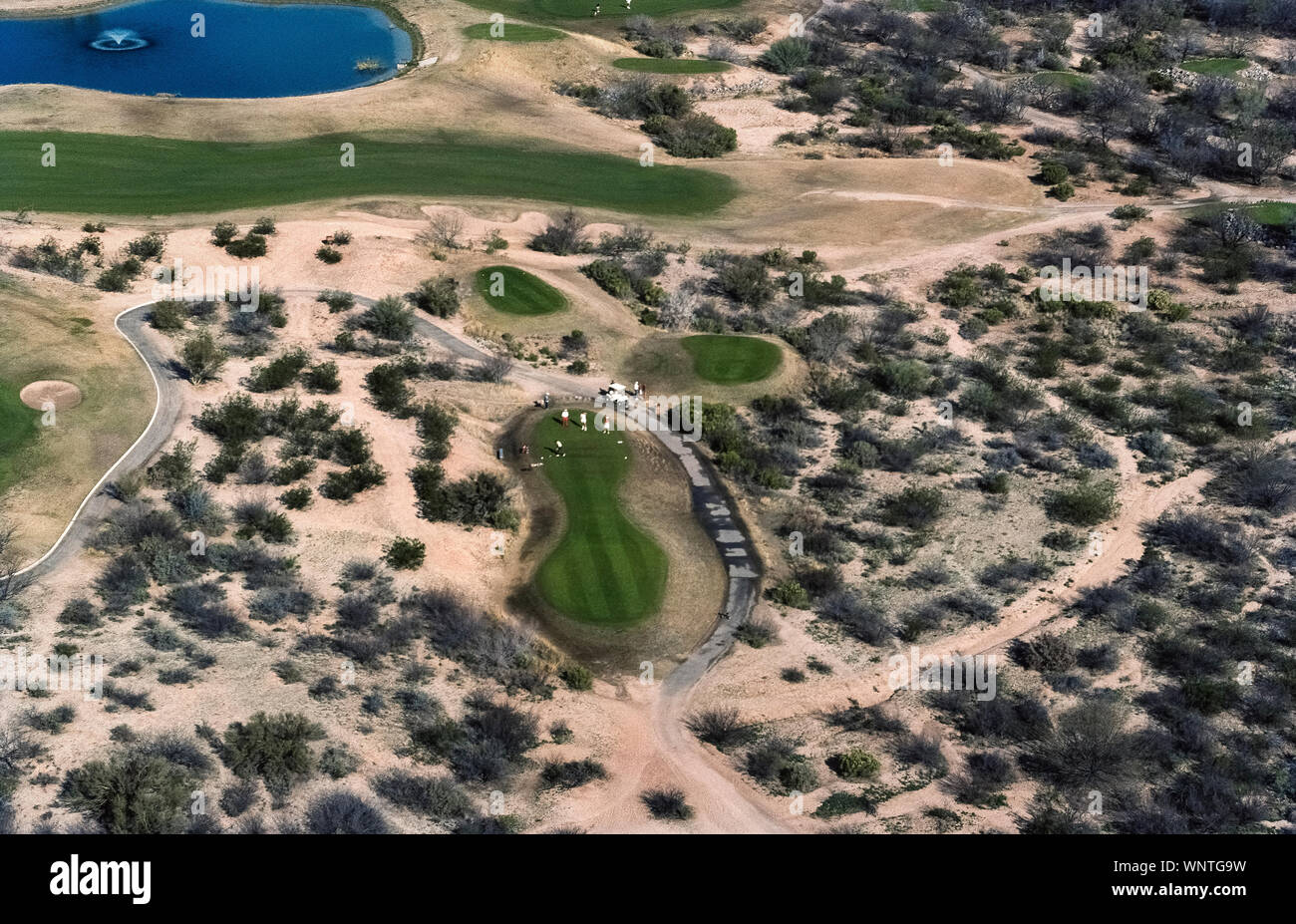 Patches of green grass tees and fairway and a blue water reservoir add ...