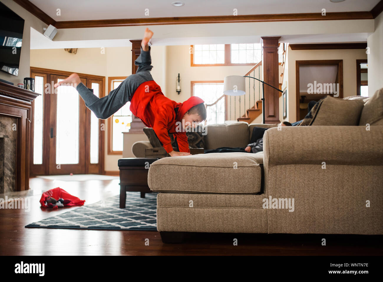 Young boy doing handstand on couch in living room during winter Stock ...