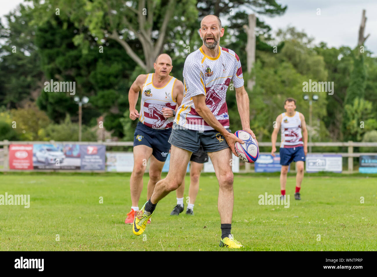 Amateur touch rugby player (male, 40-50 y) prepares to pass the ball to ...
