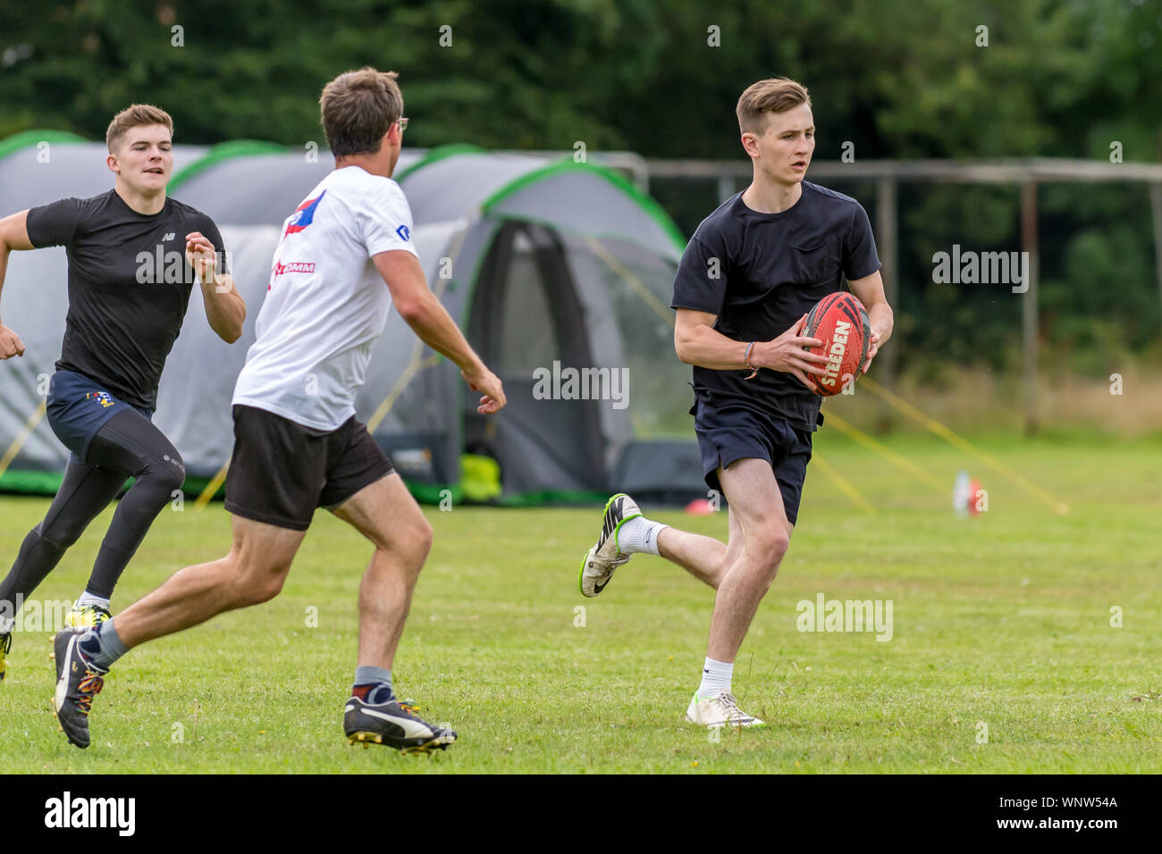 Amateur touch rugby player (male, 20 y) running with rugby ball in ...