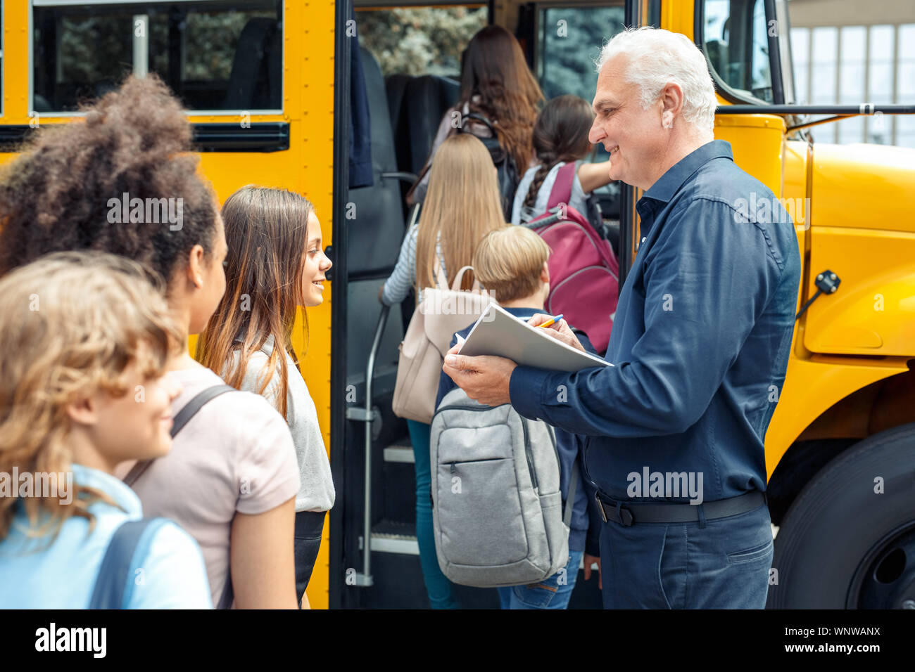 Classmates going into school bus while driver checking attendance ...