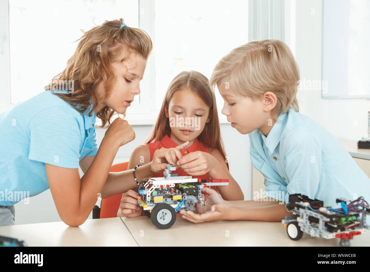 Robotics. Children having class sitting making robots connecting wires ...