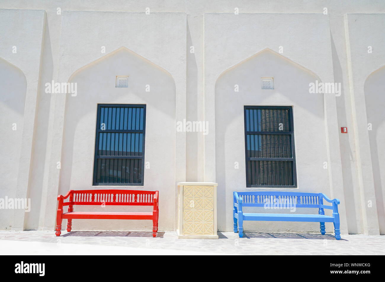 Red and blue bench seats outide white building with Arabic or Islamic ...