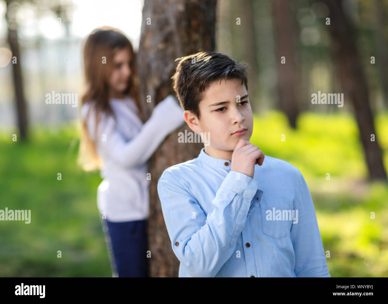 Boy and girl playing hide and seek in the park. Girl watching on ...
