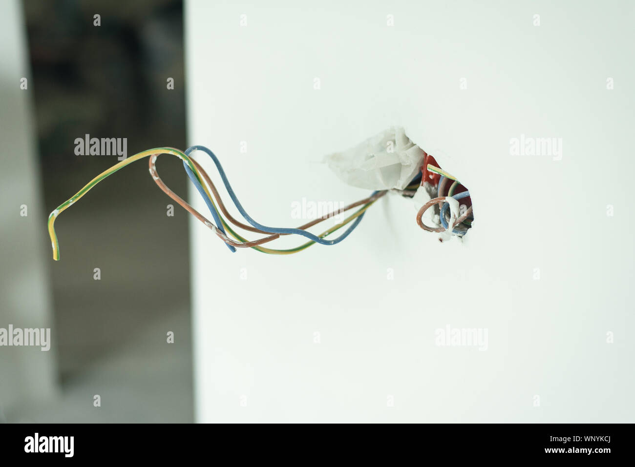 protruding wires from the outlet. Unfinished home repair on a white ...