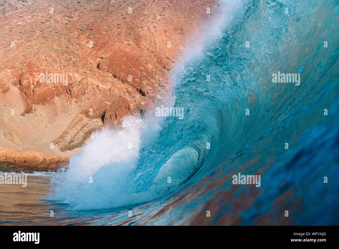 Barrel of a turquoise wave and red cliff background Stock Photo - Alamy
