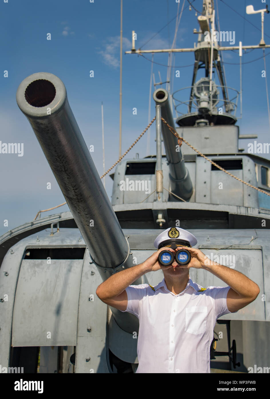 A sailor officer on battleship is looking with binocular at the white ...