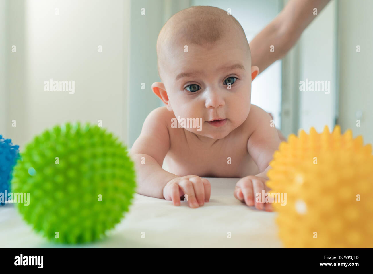 Funny little baby playing with rubber balls. The child learns the world ...