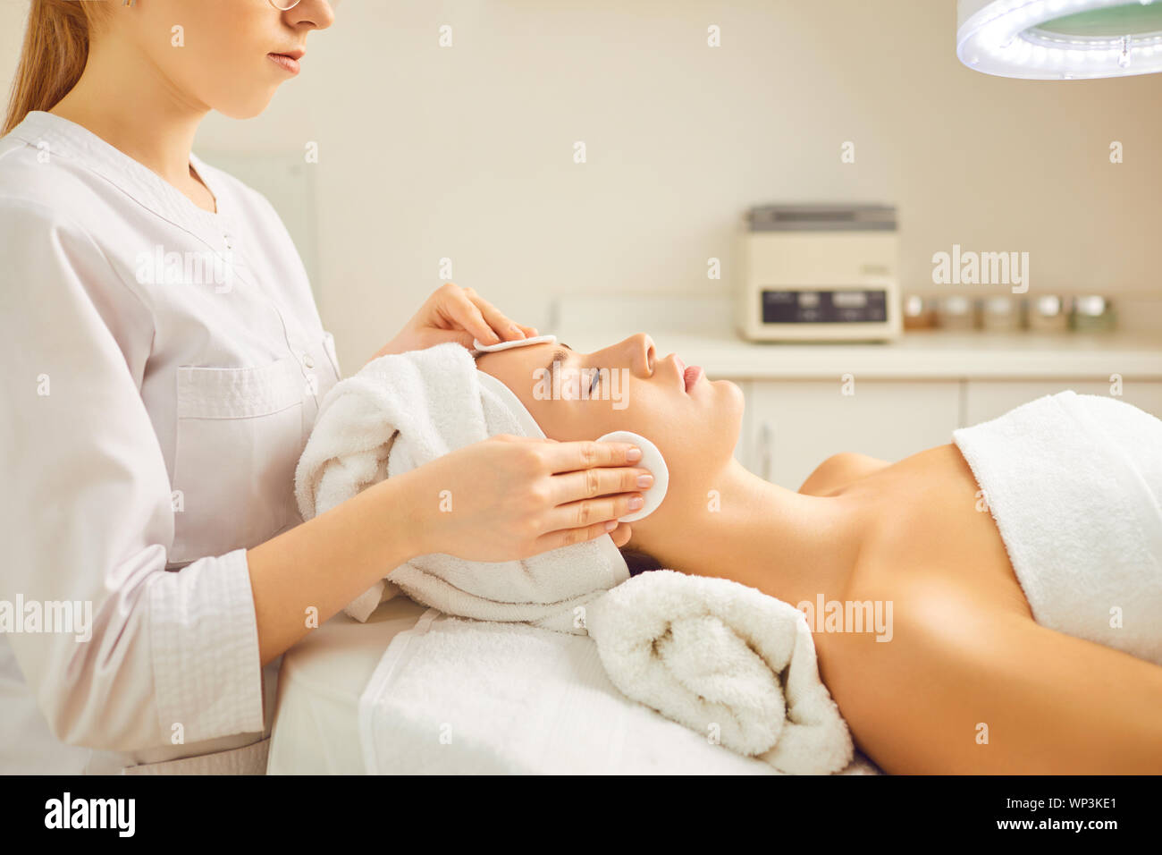 Beautician makes cleaning the face of a woman in the cosmetology office ...