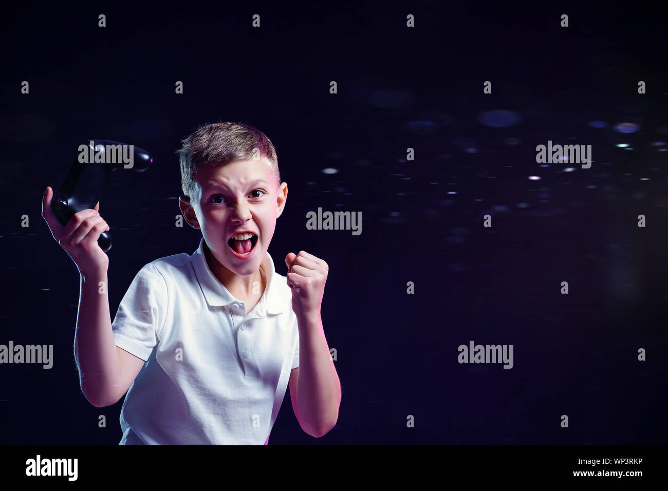 Cheerful kid with open mouth and joystick shouting for joy after ...