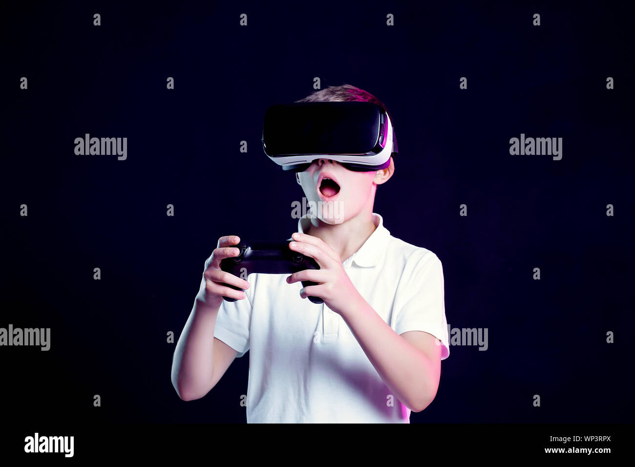 Excited kid in white t-shirt and virtual reality headset standing ...
