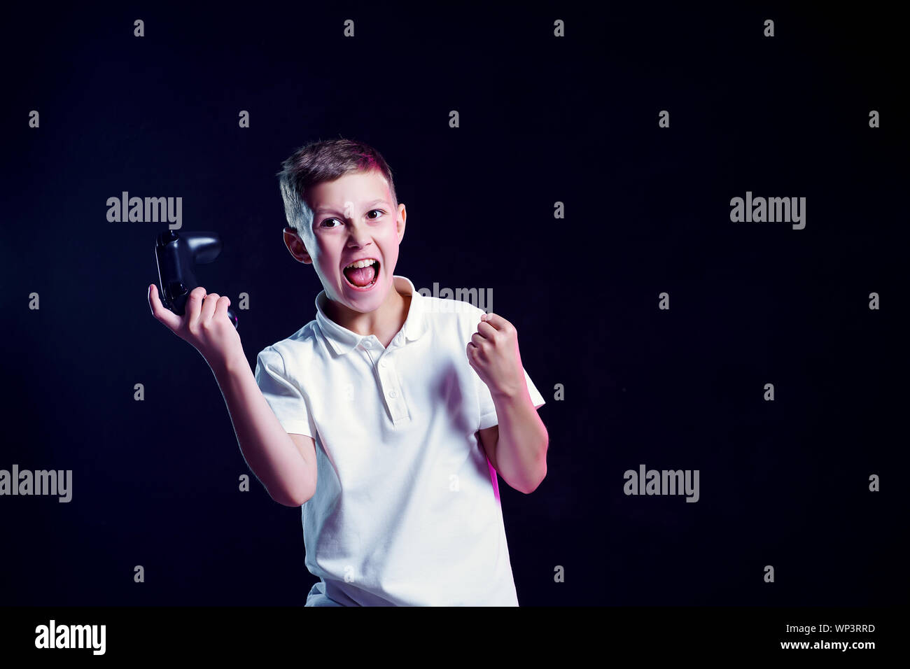 Cheerful kid with open mouth and joystick shouting for joy after ...