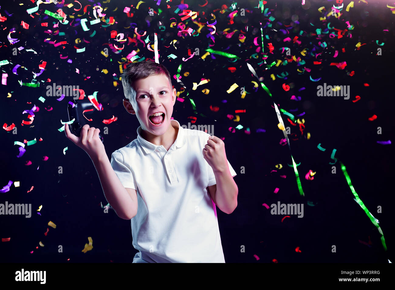 Cheerful kid with open mouth and joystick shouting for joy after ...