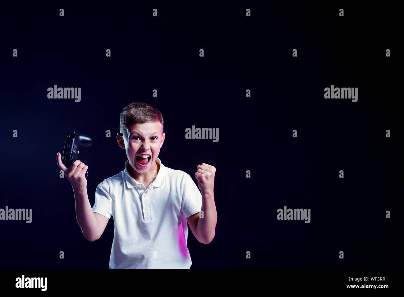 Cheerful kid with open mouth and joystick shouting for joy after ...