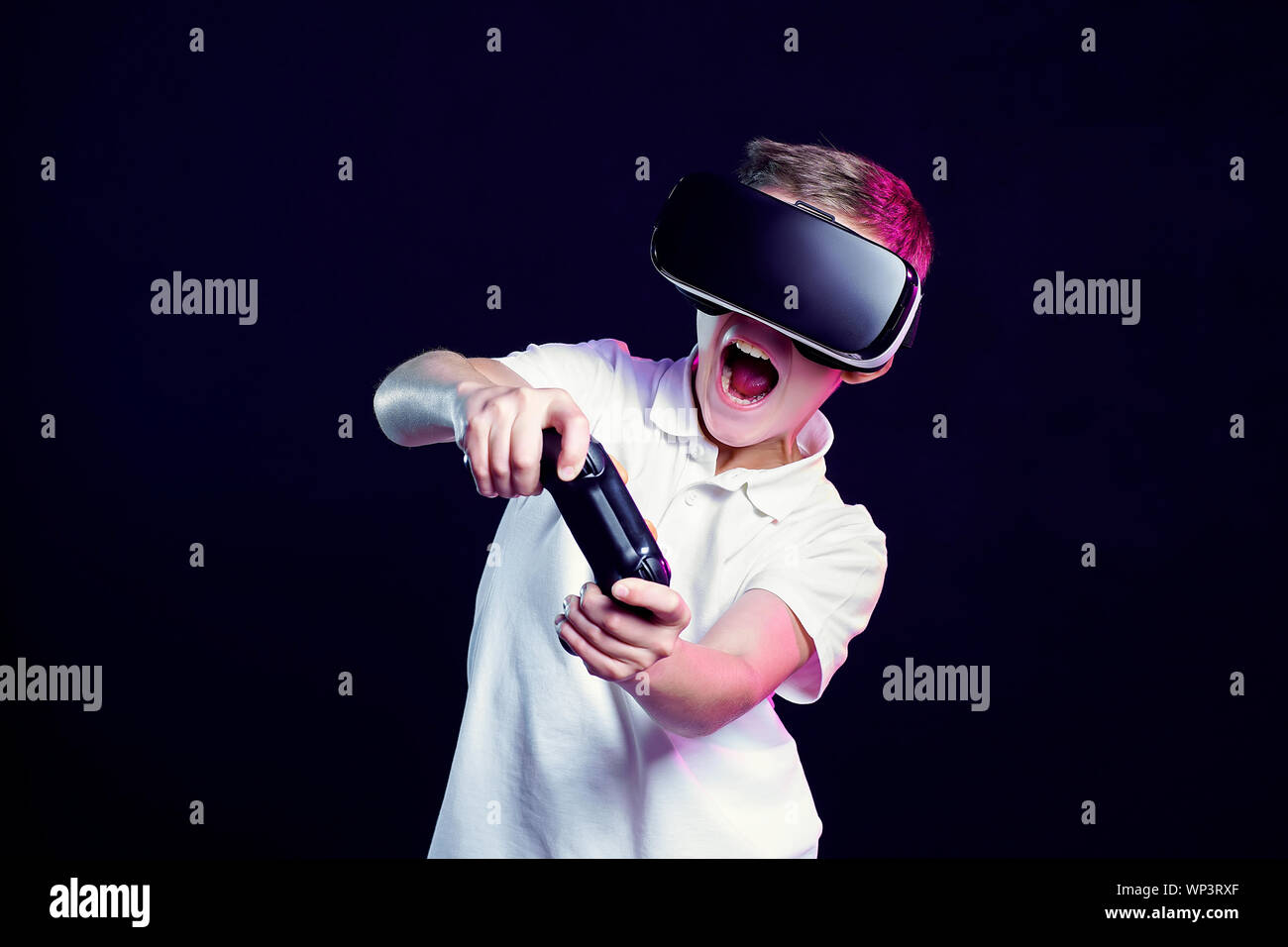 Excited kid in white t-shirt and virtual reality headset standing ...