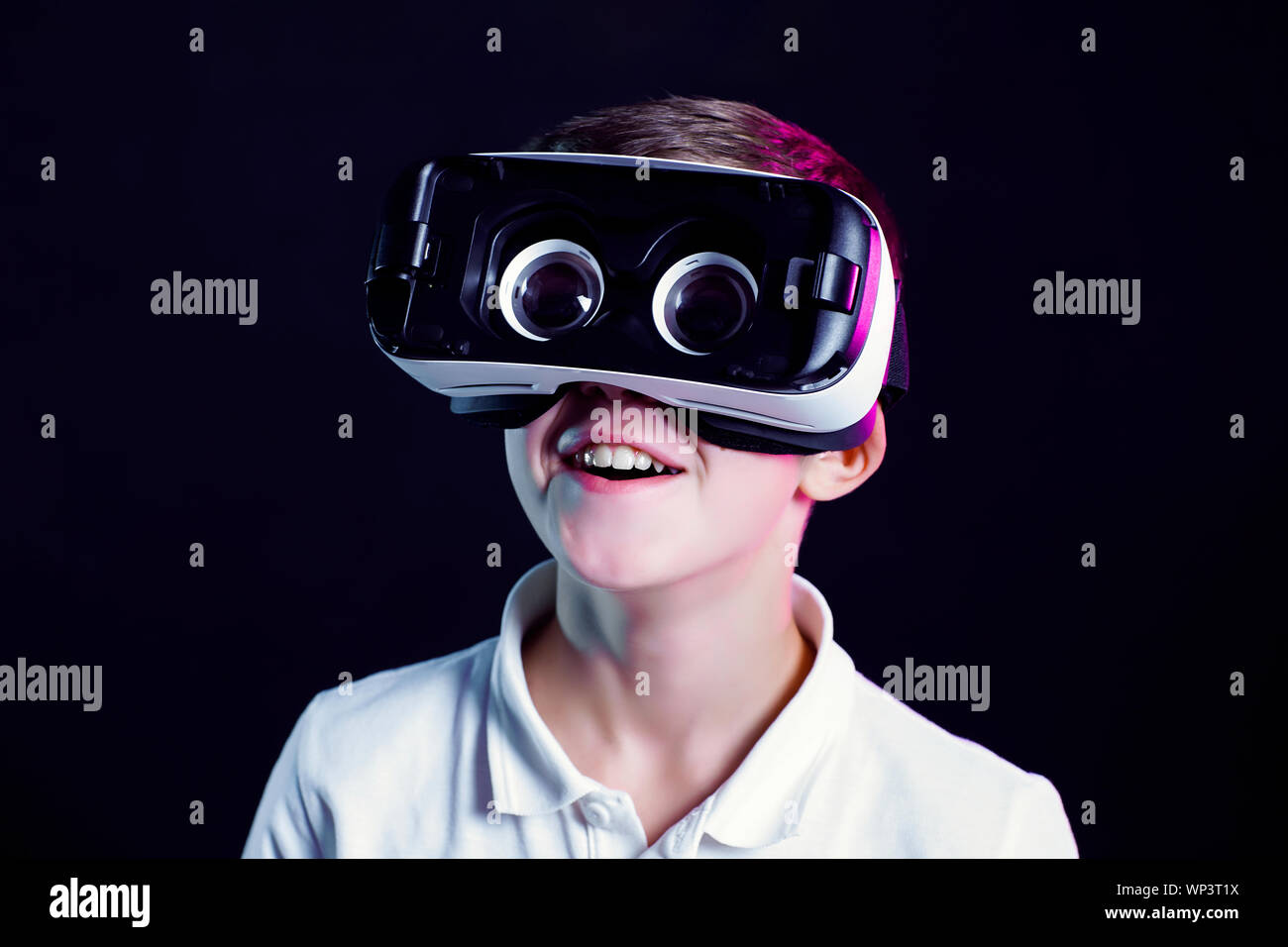 Side view of excited kid in white t-shirt and virtual reality headset ...