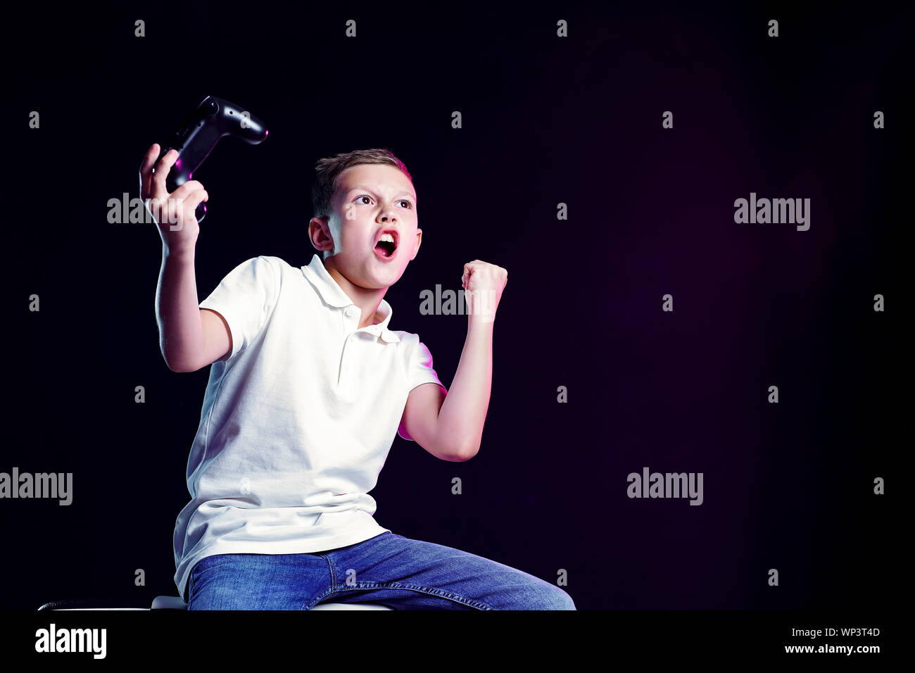 Cheerful kid with open mouth and joystick shouting for joy after ...
