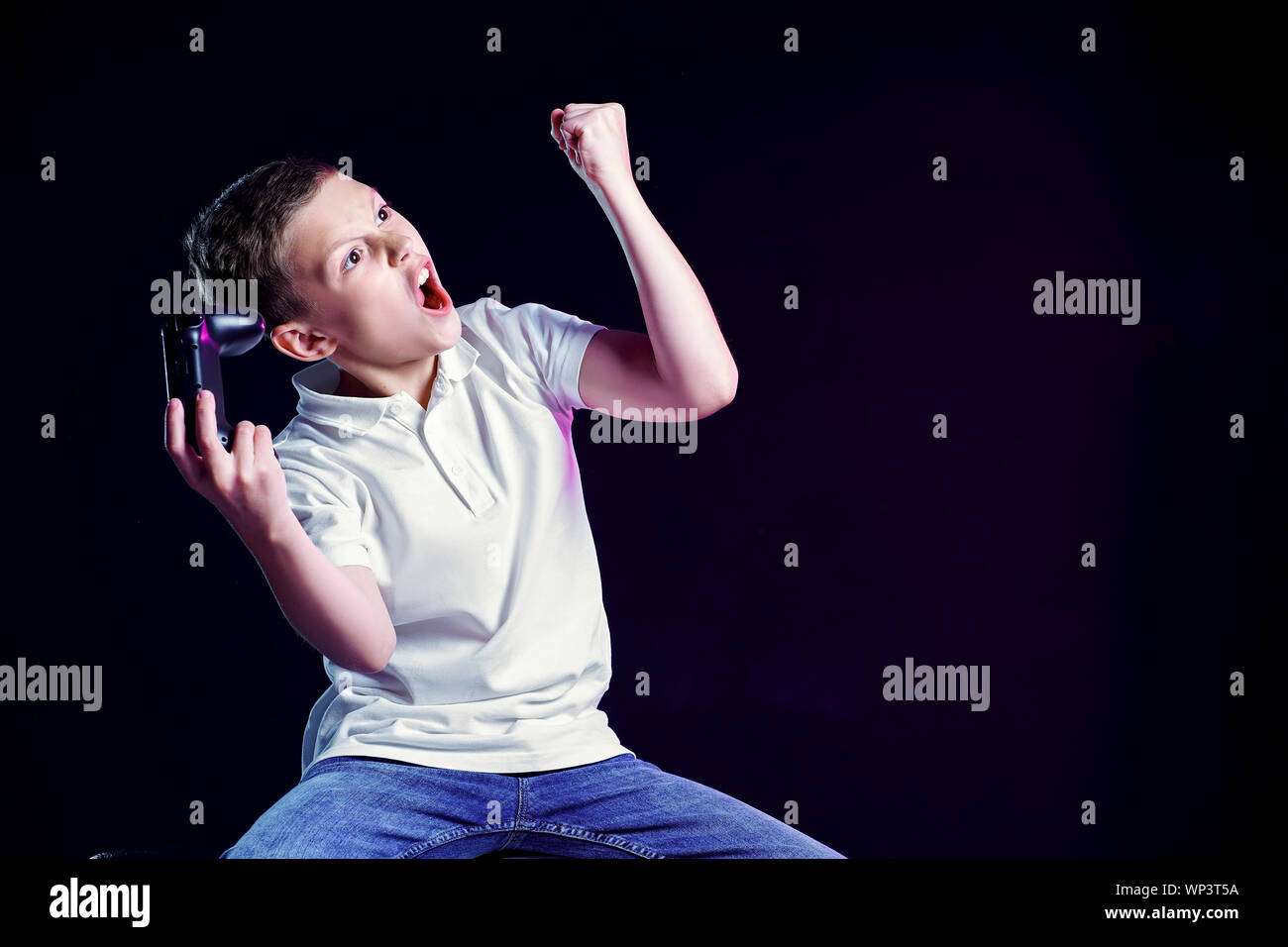 Cheerful kid with open mouth and joystick shouting for joy after ...