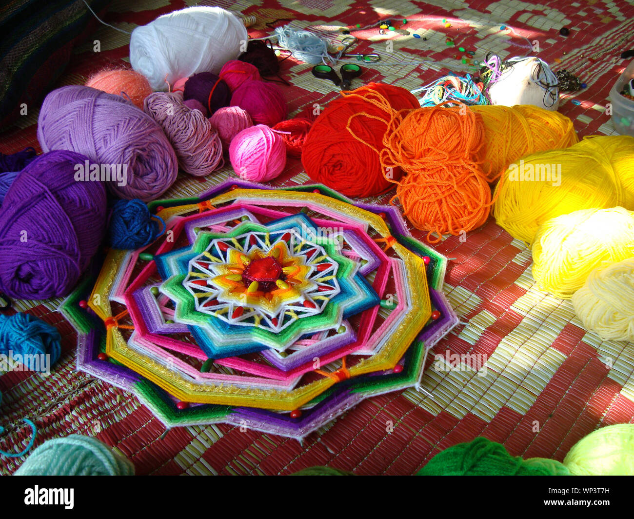 Beautiful mandala made of threads lies surrounded by balls of thread of ...