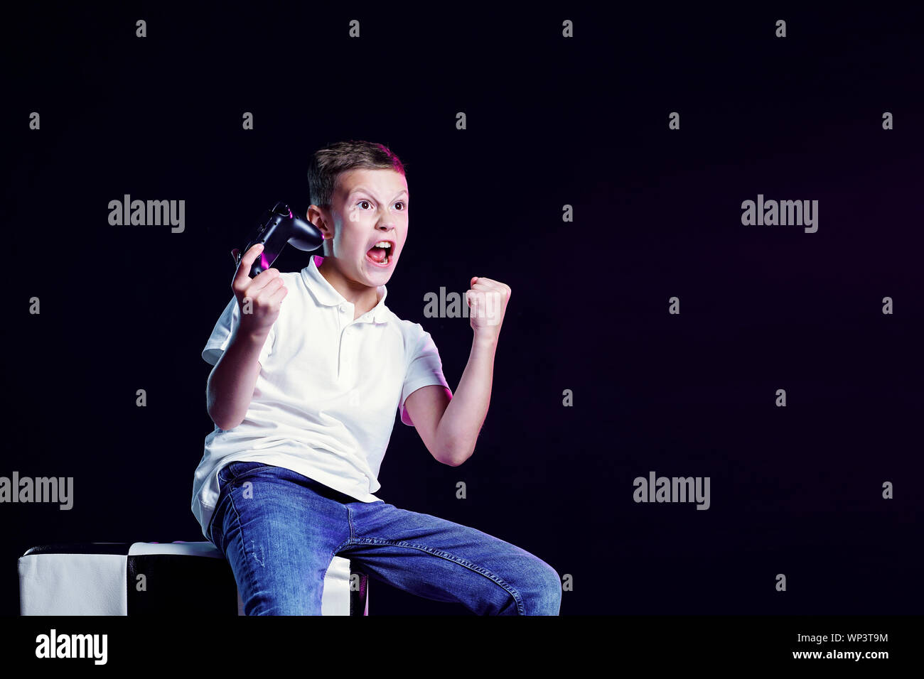 Cheerful kid with open mouth and joystick shouting for joy after ...