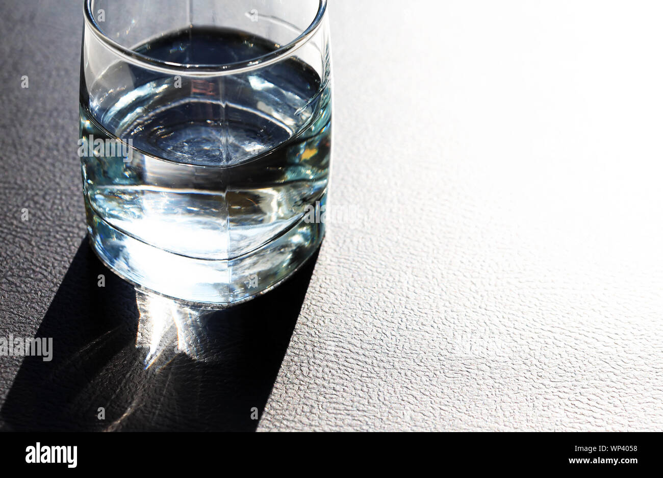 Half glass of water on dark background with shadow Stock Photo - Alamy