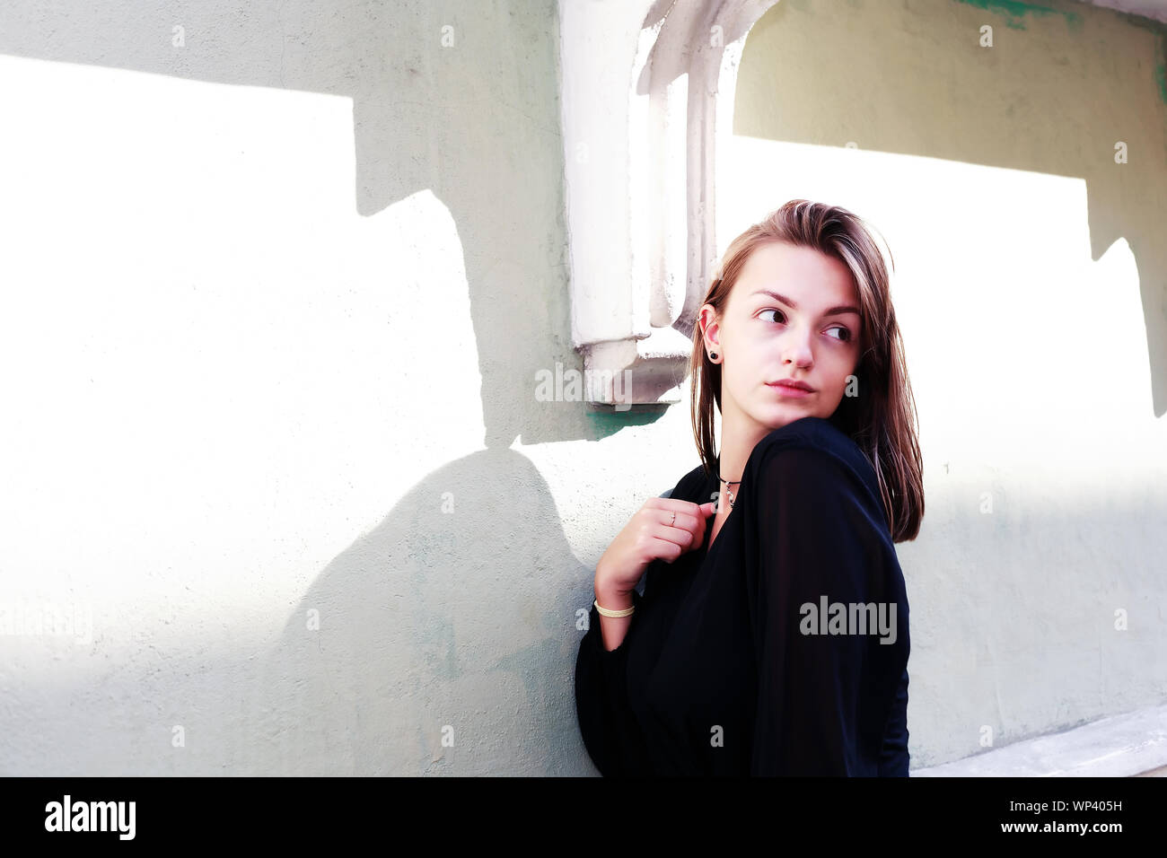 Beautiful young woman against building wall with shadow Stock Photo - Alamy