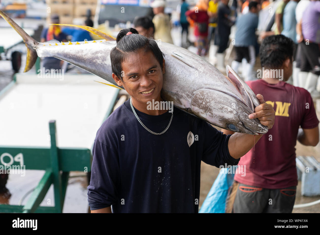 A man carrying a large Yellowfin Tuna on his shoulder,within the ...