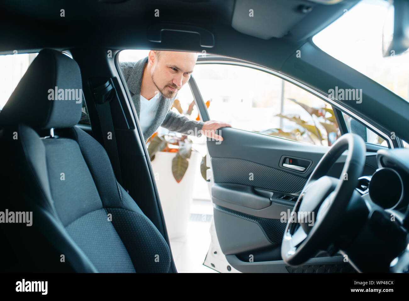 Man watching the interior of new car in showroom Stock Photo - Alamy