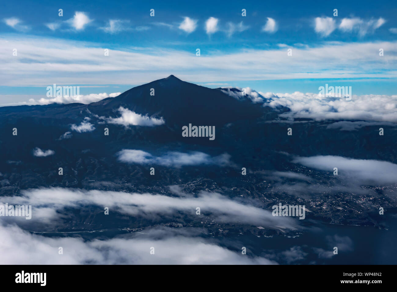 Dramatic view of Mount Teide from the air above the clouds silhouetted ...