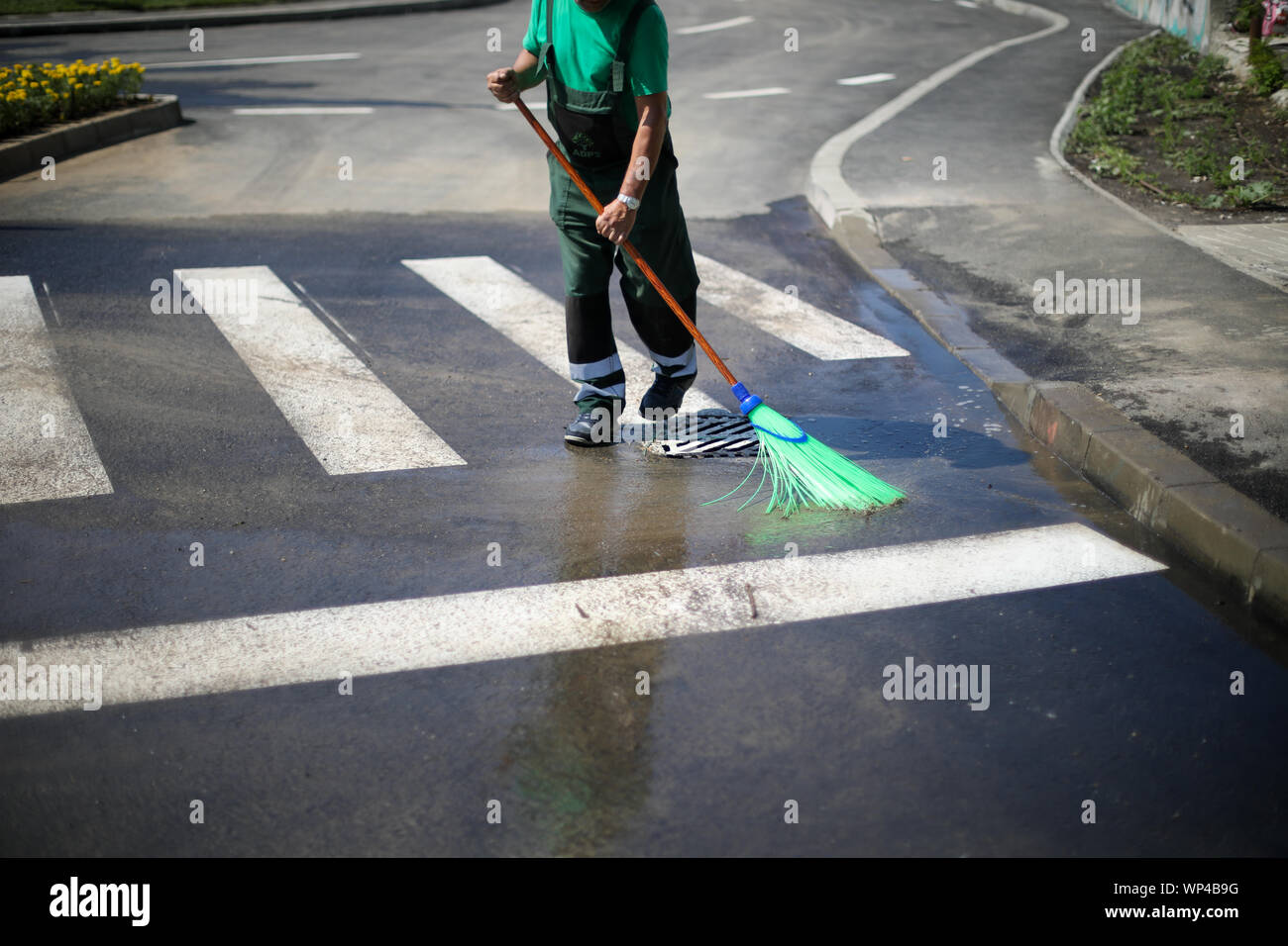 Street sweeper cleaning city sidewalk with water from a hose and a ...