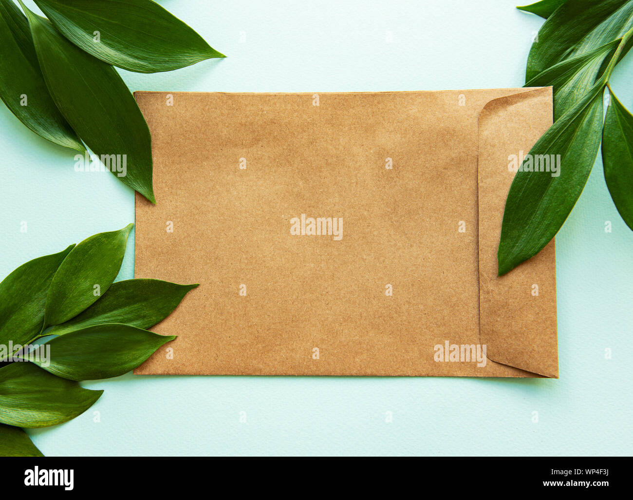 Craft envelope on a mint background with green leaves. Minimalistic ...