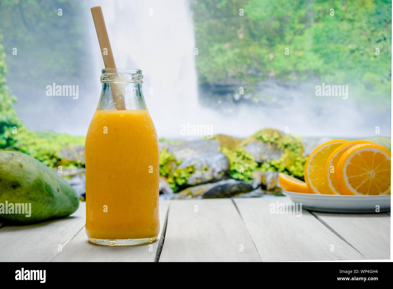 Apple and mango fruit juice in a bottle with bamboo straw and tropical ...