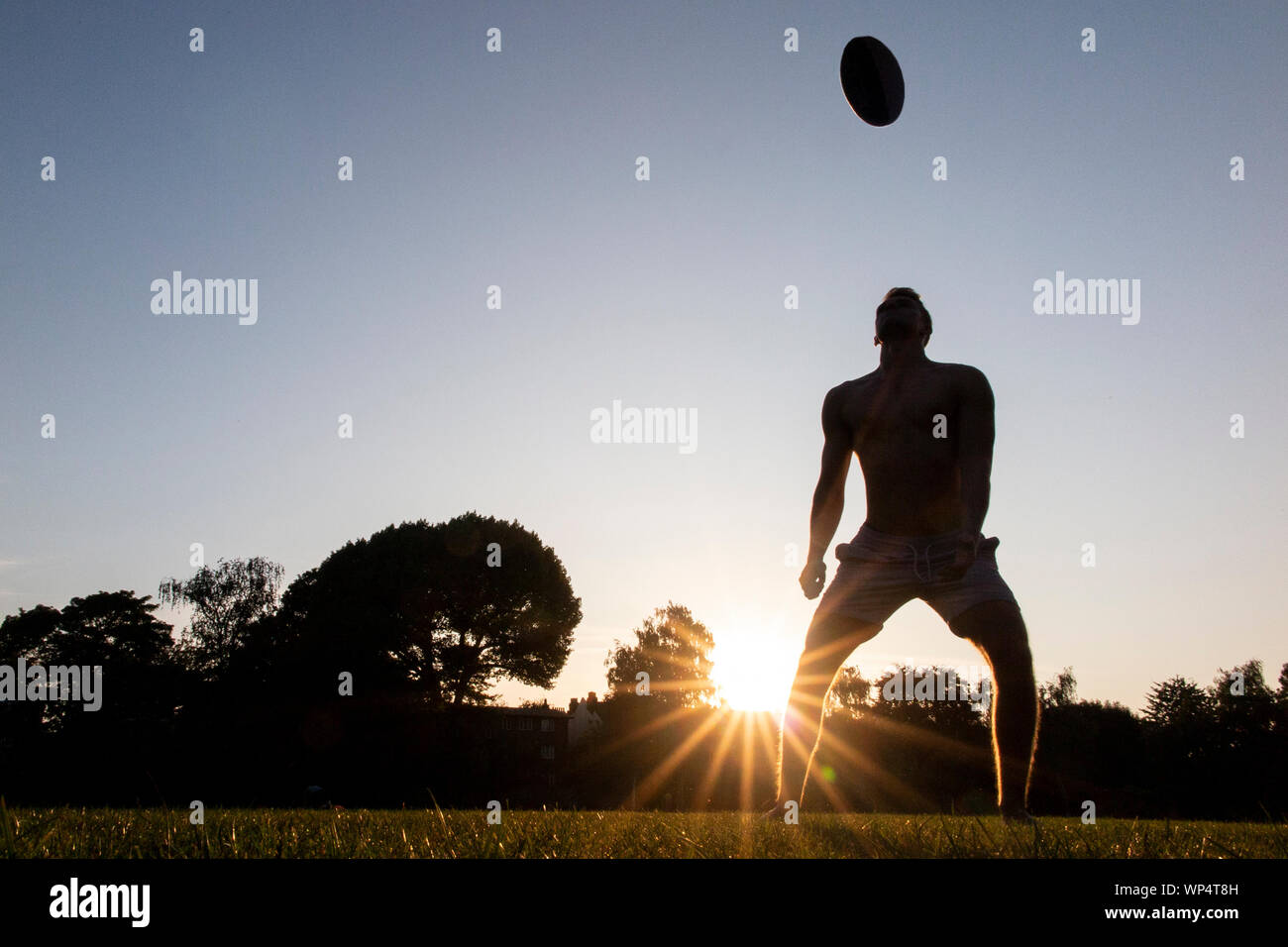 A boy catching and passing a rugby ball on a summer's day in a park ...