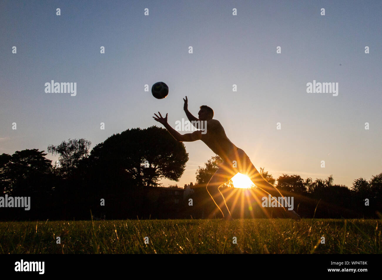 A boy catching and passing a rugby ball on a summer's day in a park ...