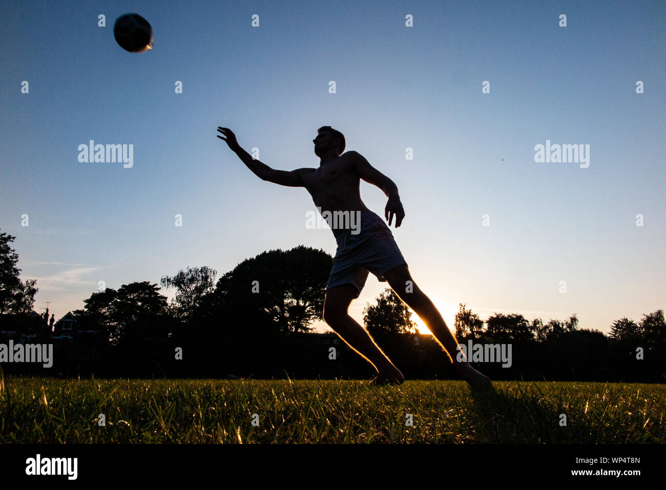 A boy catching and passing a rugby ball on a summer's day in a park ...