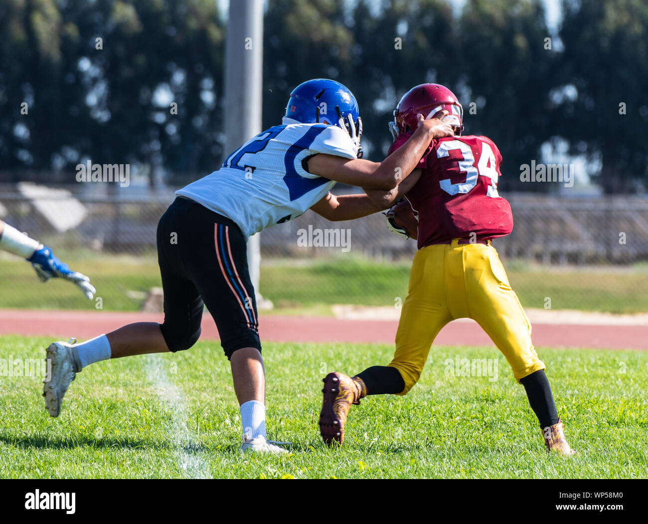Defensive player has offensive running back with ball wrapped up in his ...
