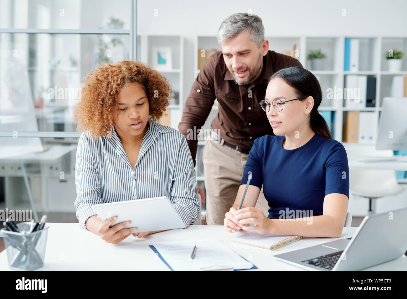 Group of young contemporary confident office workers working over ...