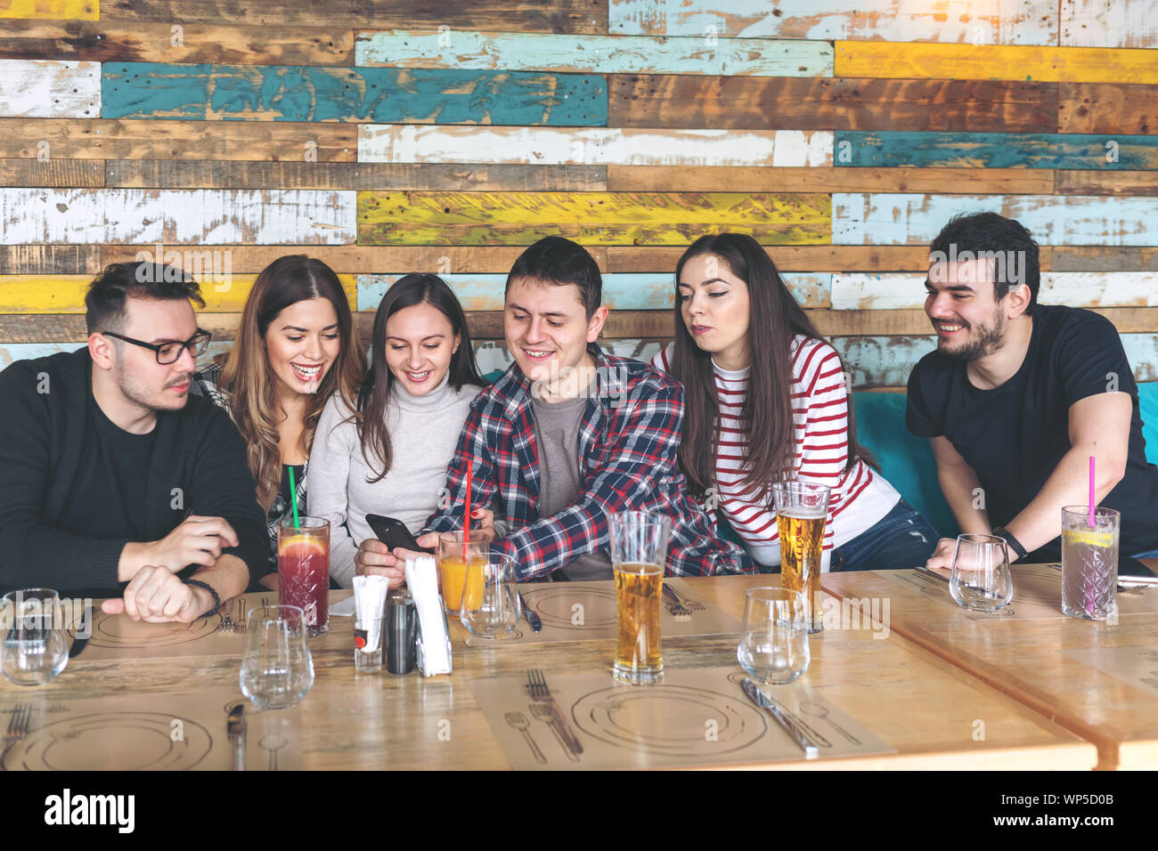 Group of best friends watching videos on smartphone at modern pub Stock ...