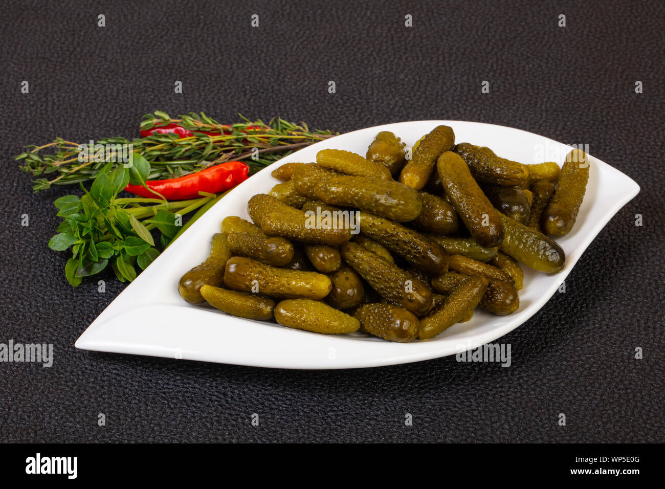 Pickled small cucumbers in the bowl served herbs Stock Photo - Alamy