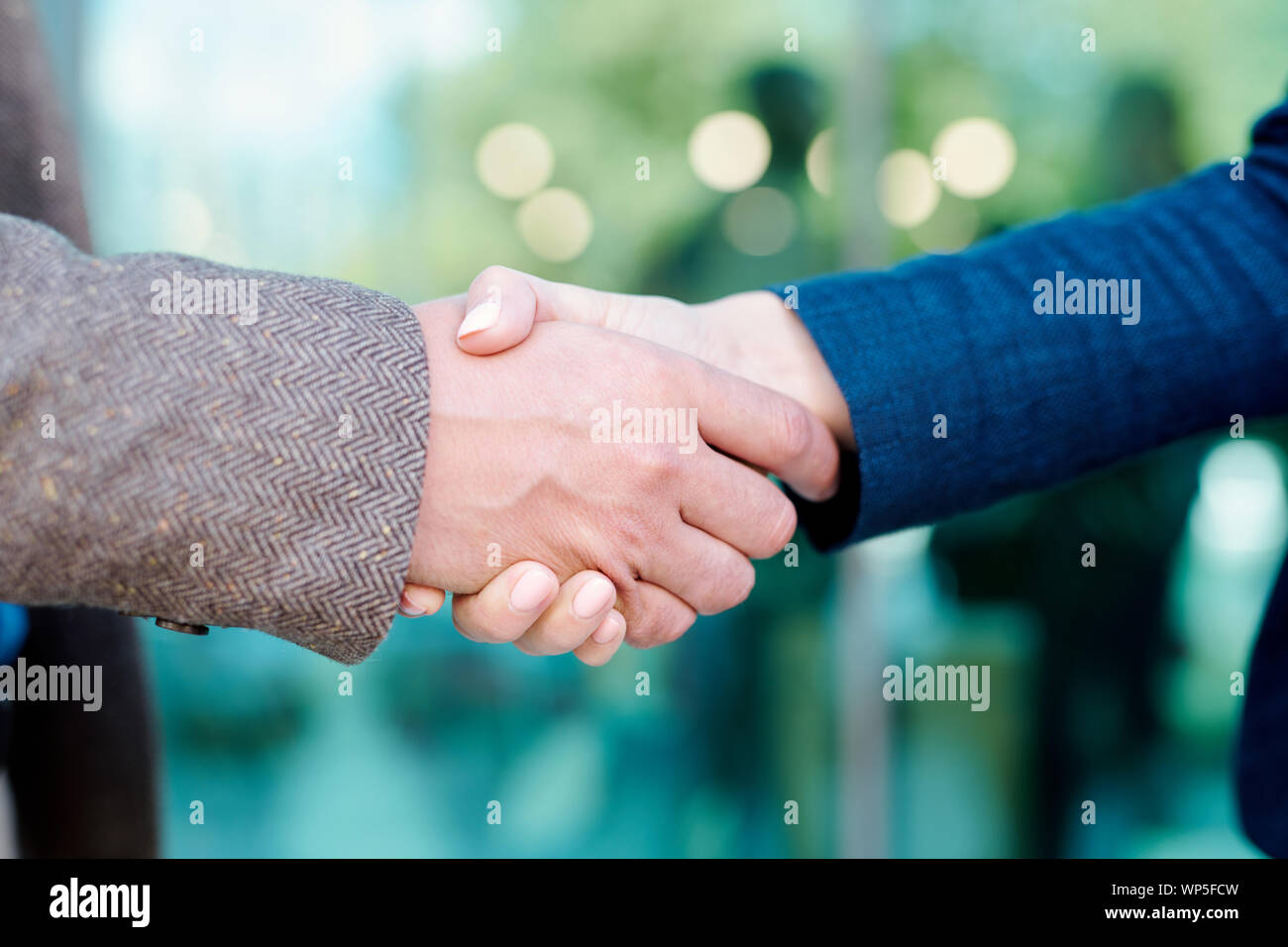 Hands of young contemporary employees in handshake symbolizing ...