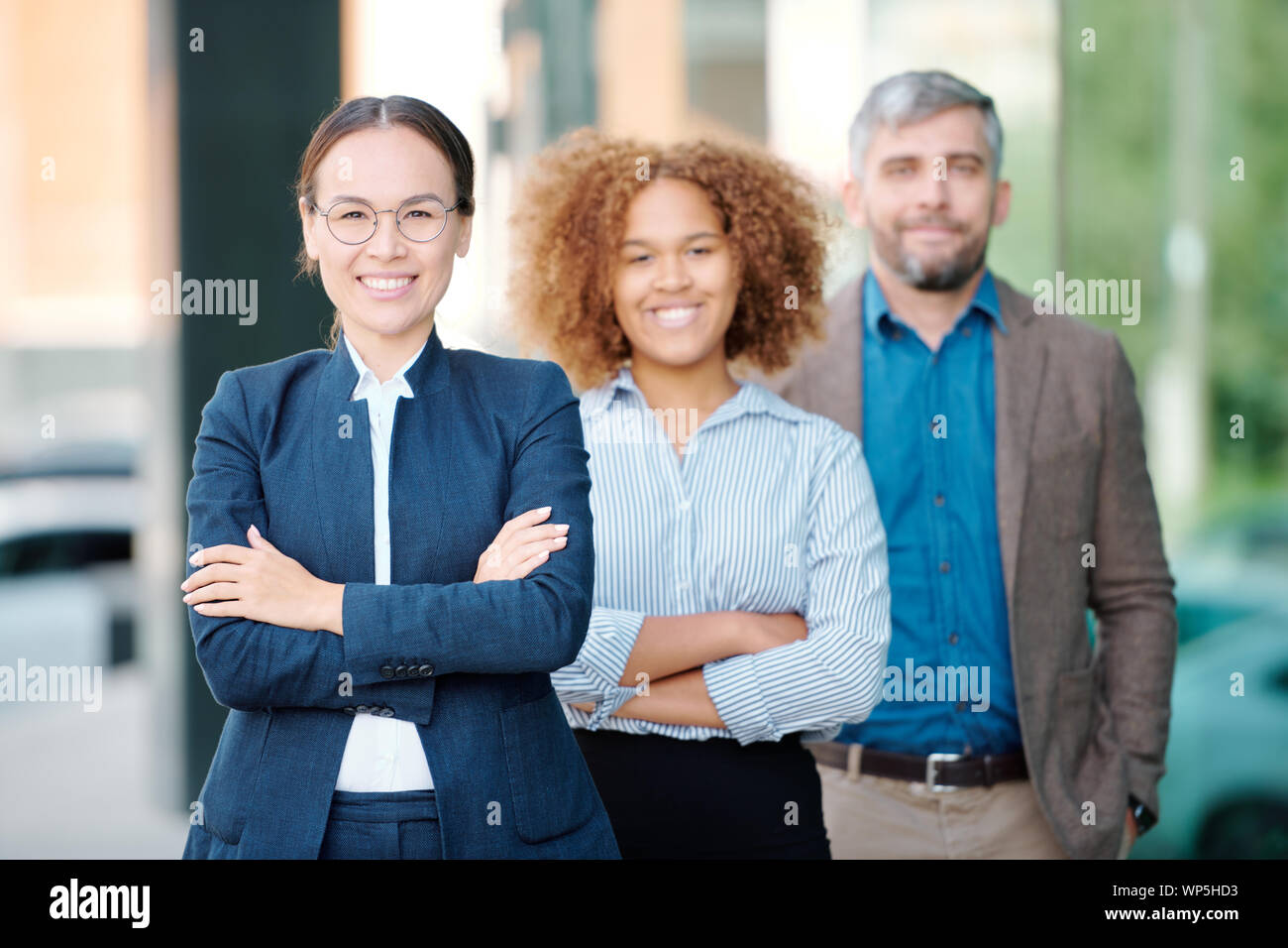Young cheerful business leader in formalwear and her team behind ...