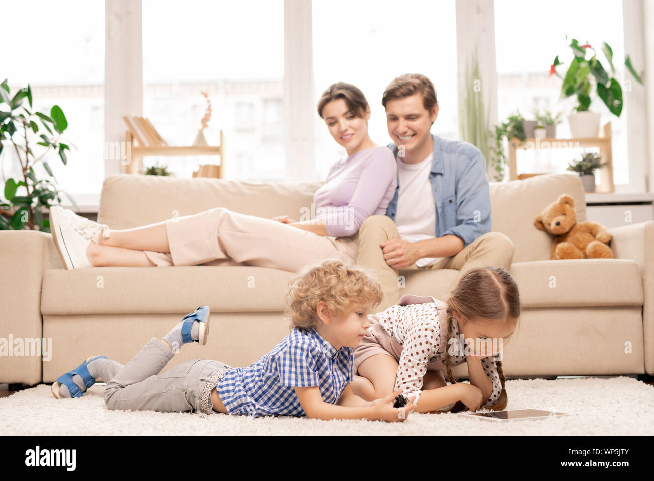 Two cute elementary age kids with touchpad lying on the floor of living ...