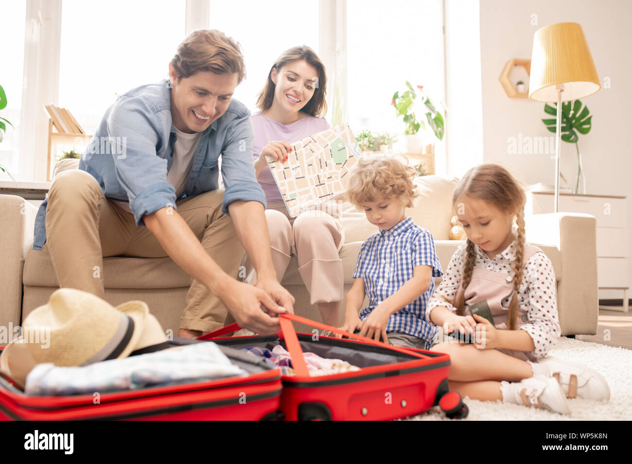 Young couple and two little kids preparing things before travel Stock ...
