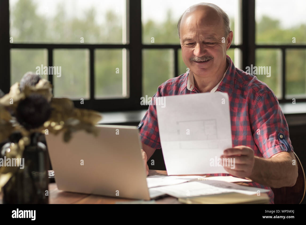 Senior hispanic man with mustache holding plan of new flat deciding to ...