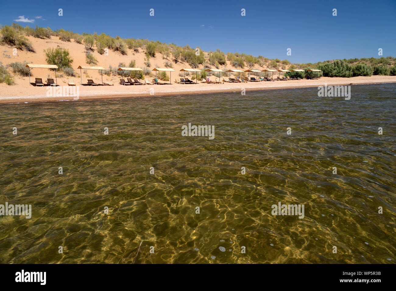 Sun loungers and canopies on the western shores of Lake Aidarkul near ...