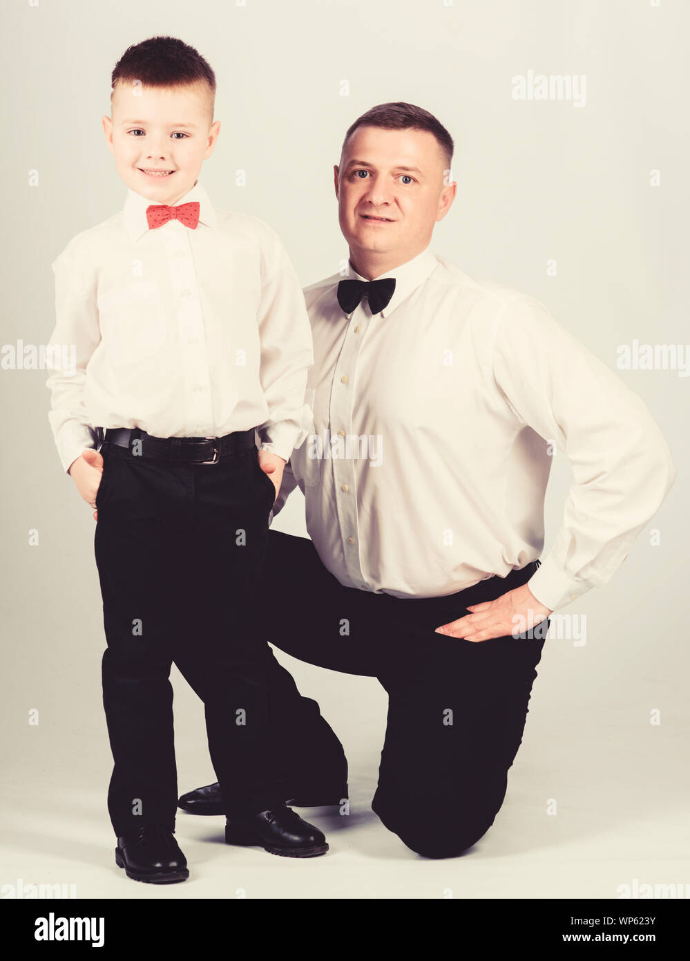 Formal event. Little son following fathers example of noble man ...