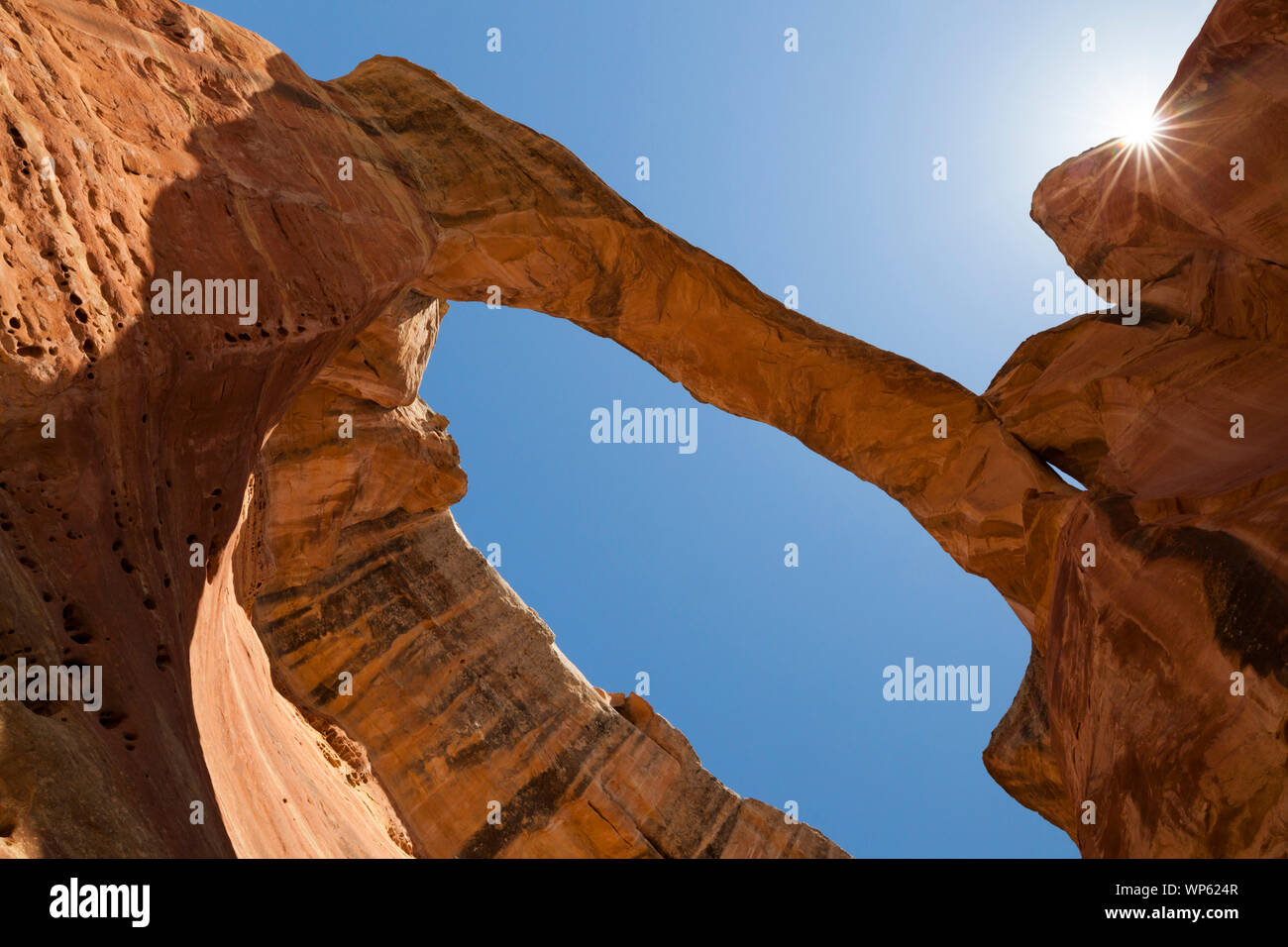 Dramatic rock arch from below with sunburst, Rattlesnake Arches Trail ...