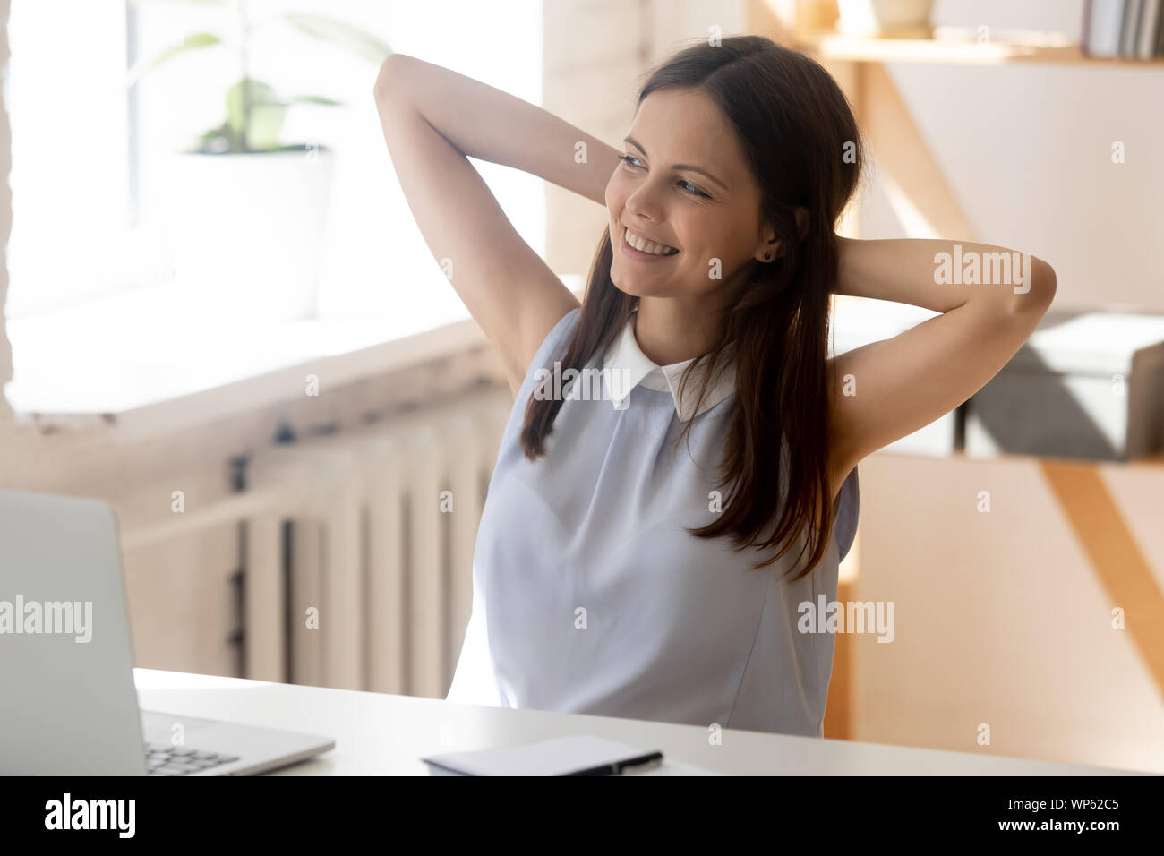 Smiling young female employee look in distance dreaming Stock Photo - Alamy